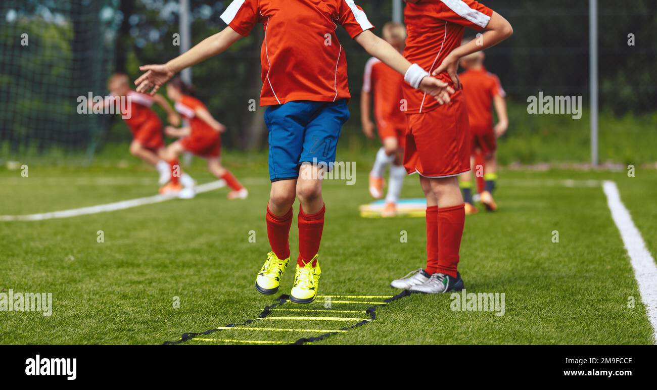 Group of children jumping over training ladder during soccer football ...