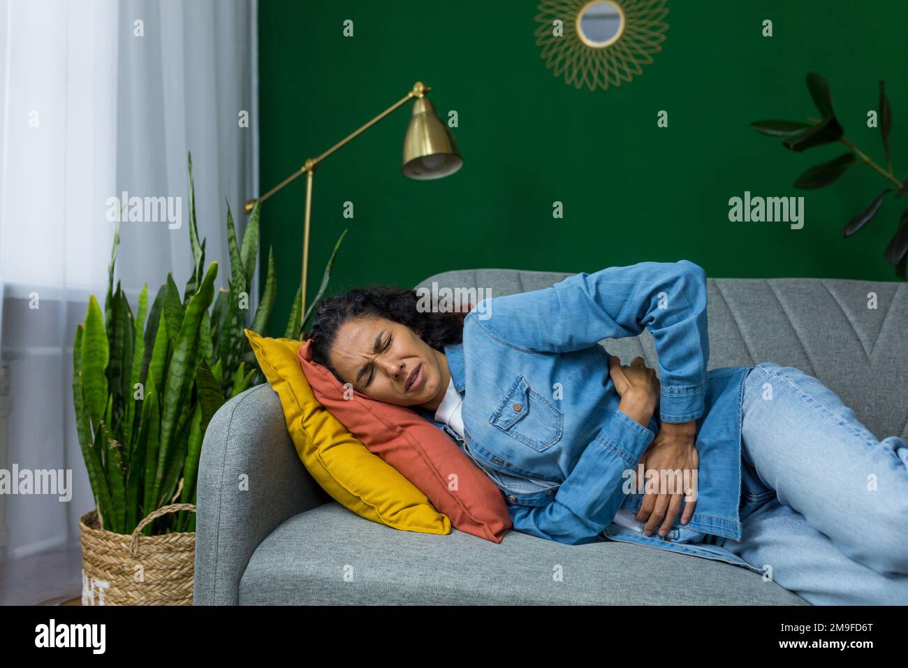 Hispanic woman sick lying on sofa in living room, woman has severe ...