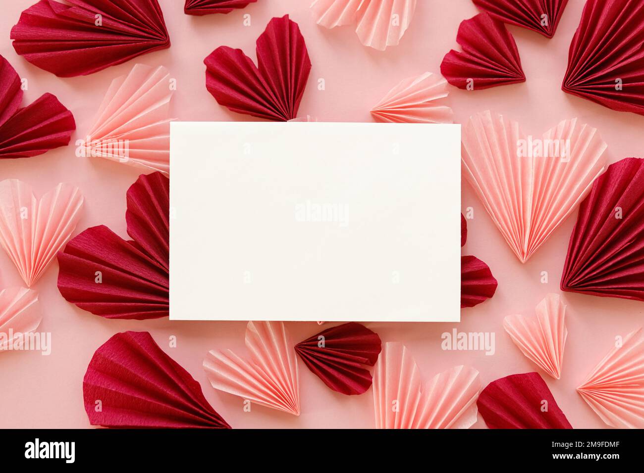Empty card and stylish red and pink hearts flat lay on pink paper ...