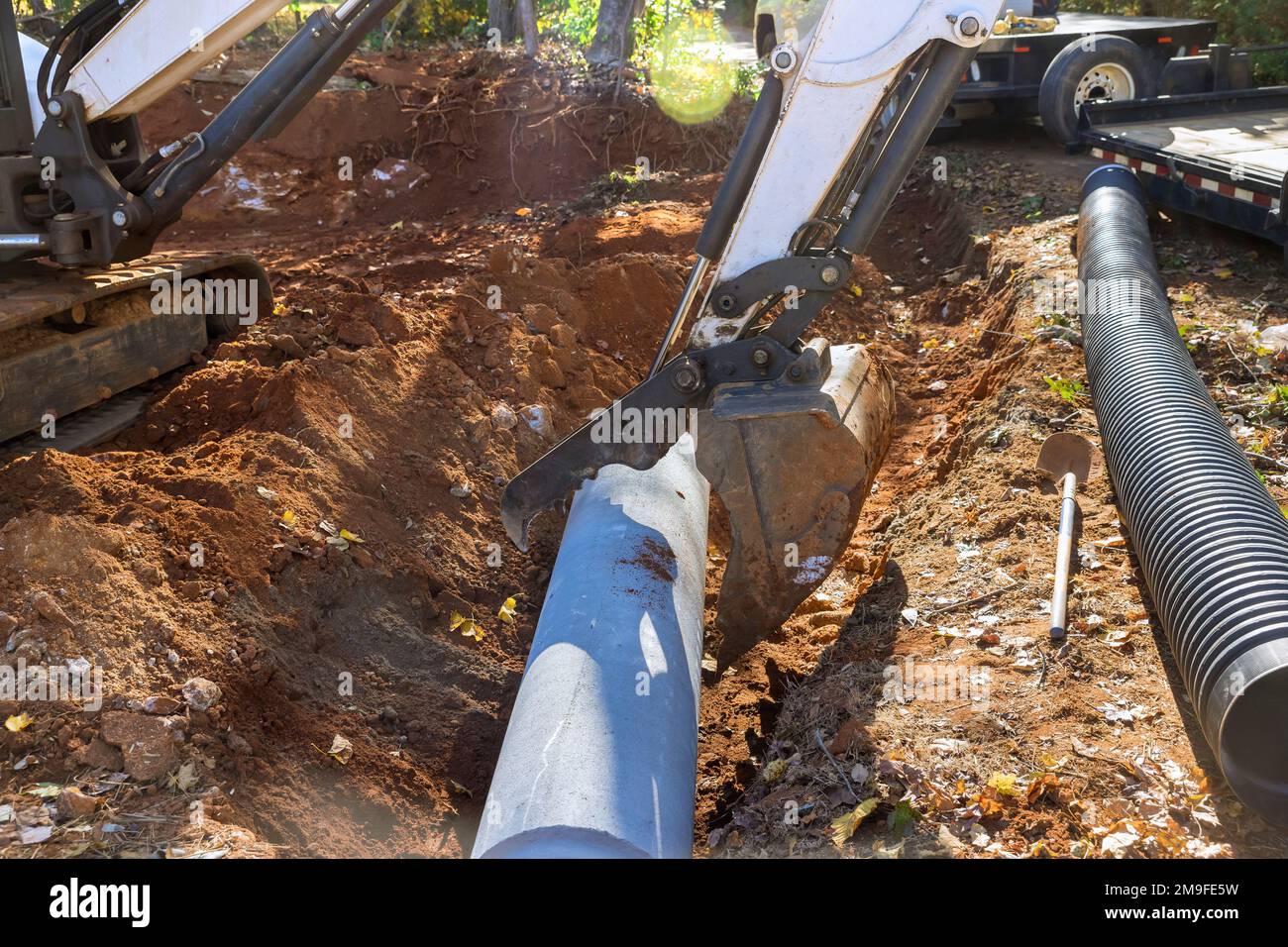 Worker who operate tractor lift sewage pipes in ground are preparing to ...
