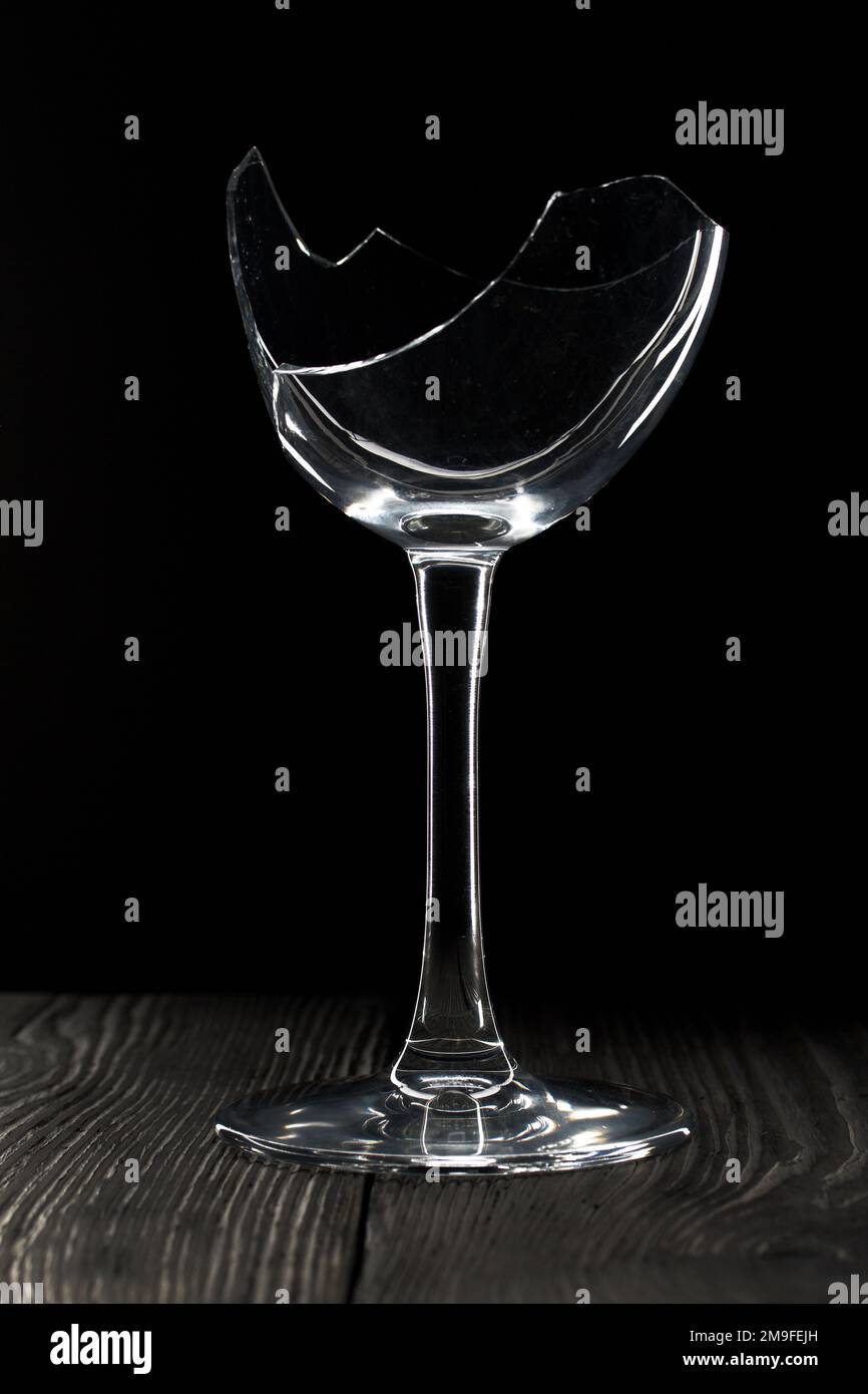 Broken glass goblet. Stands on black boards. Shot on a black background ...