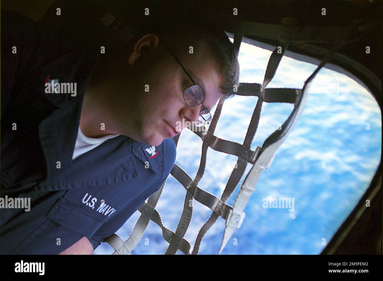 US Navy Boatswain's Mate Third Class Anthony Dick looks through an ...