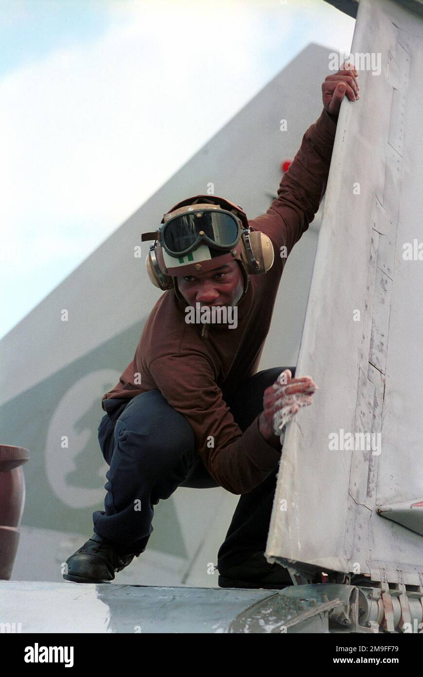 Aviation Storekeeper US Navy AIRMAN Taron Johnson scrubs down the wing ...