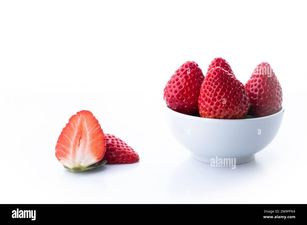 fresh strawberries inside a bowl and a strawberry cut in half Stock ...