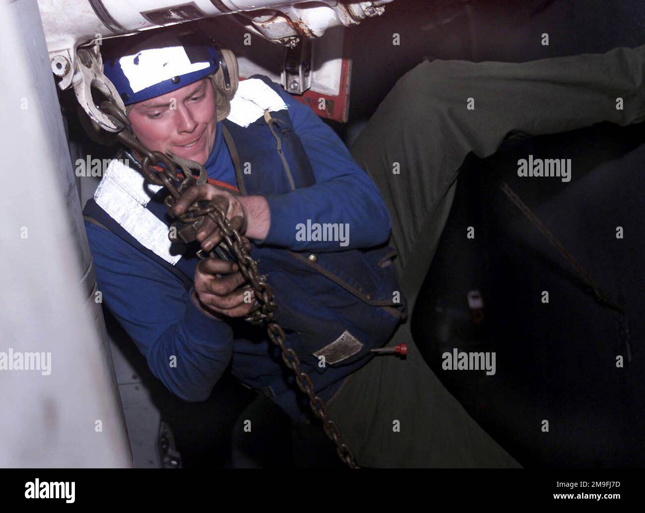 US Navy AIRMAN Casey Miles uses chains to secure a F/A-18 Hornet ...