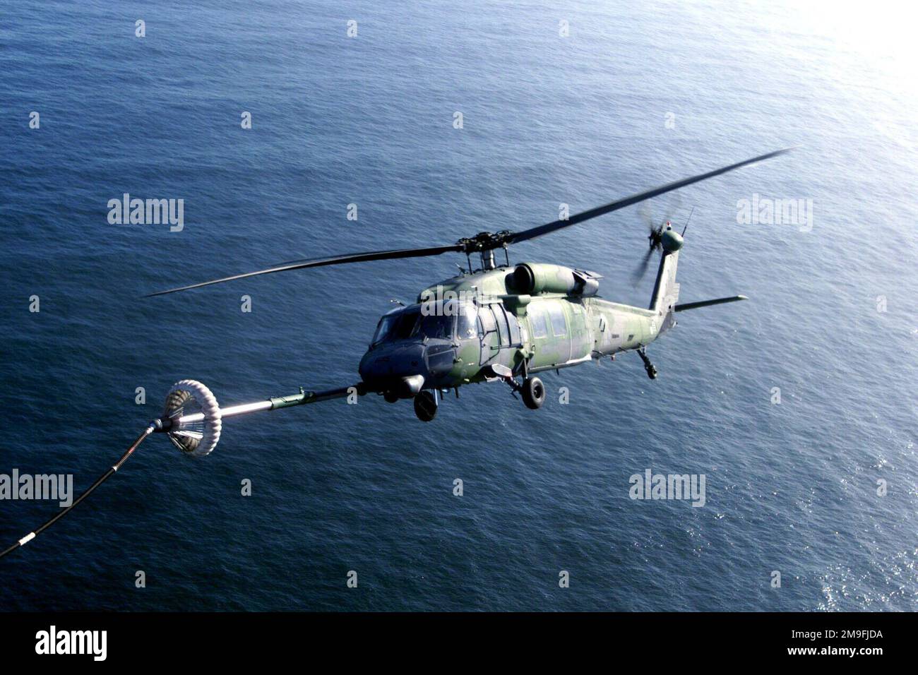 An HH-60G Pavehawk helicopter plugs into the air refueling hose from an ...