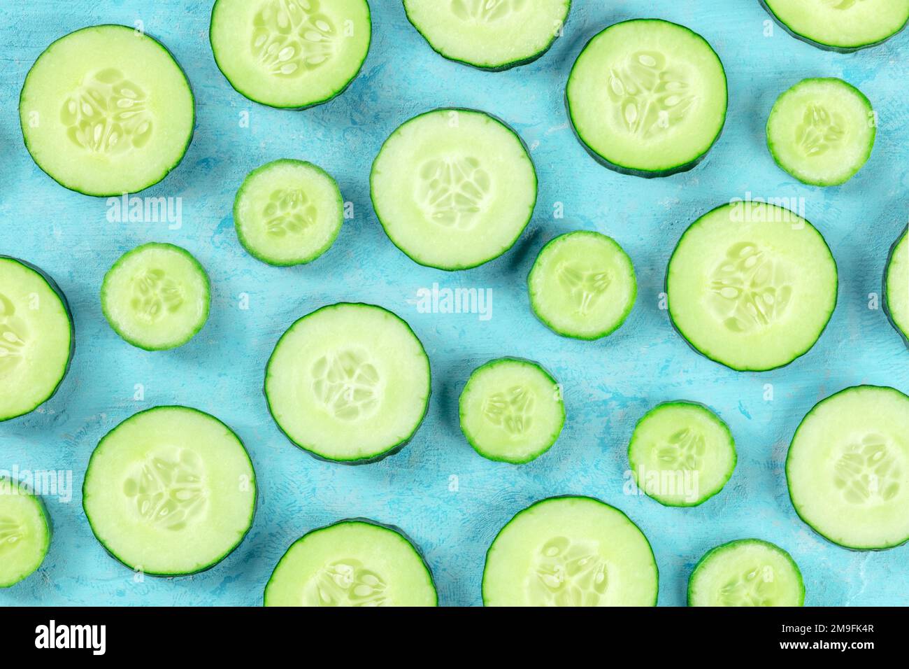 Fresh cucumber slices on a blue background, overhead flat lay shot ...