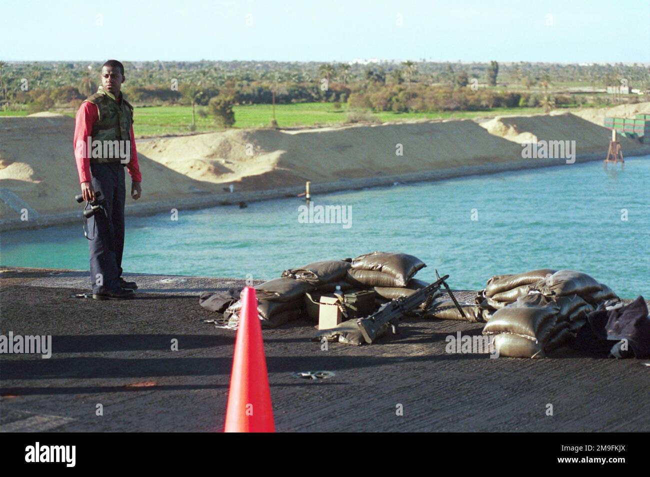 US Navy Aviation Ordnanceman Jamal Collins stands an M-60 machine gun ...