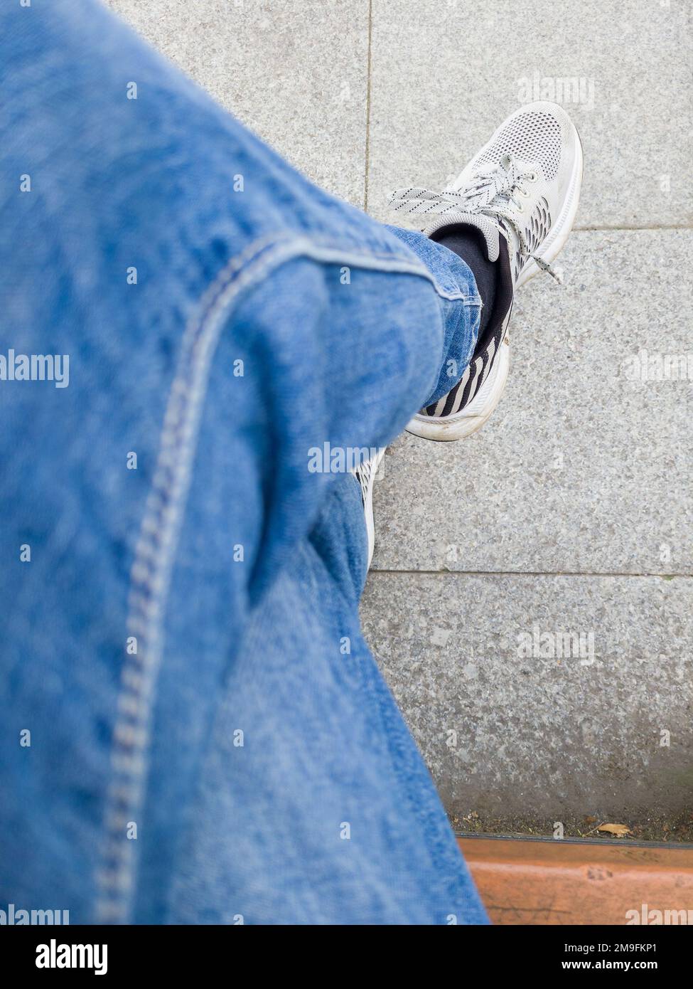 Top view of the leg in jeans and sneakers Stock Photo - Alamy