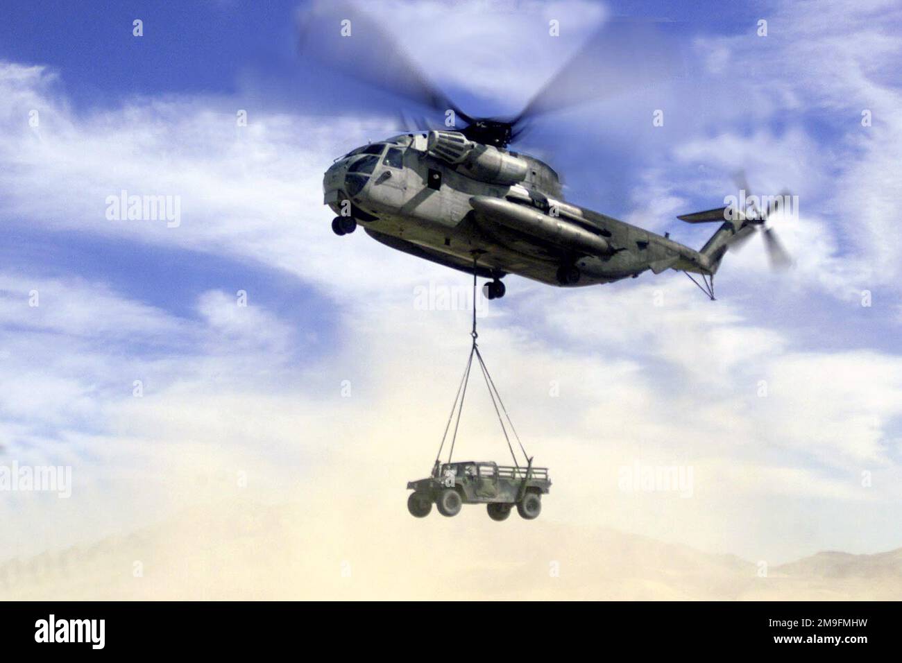 A CH-53E Super Stalion helocopter gently lowers an M998 High-Mobility ...