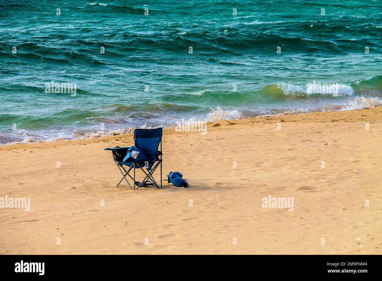 A folding chair at the beach surrounded by the sea under the sunlight ...