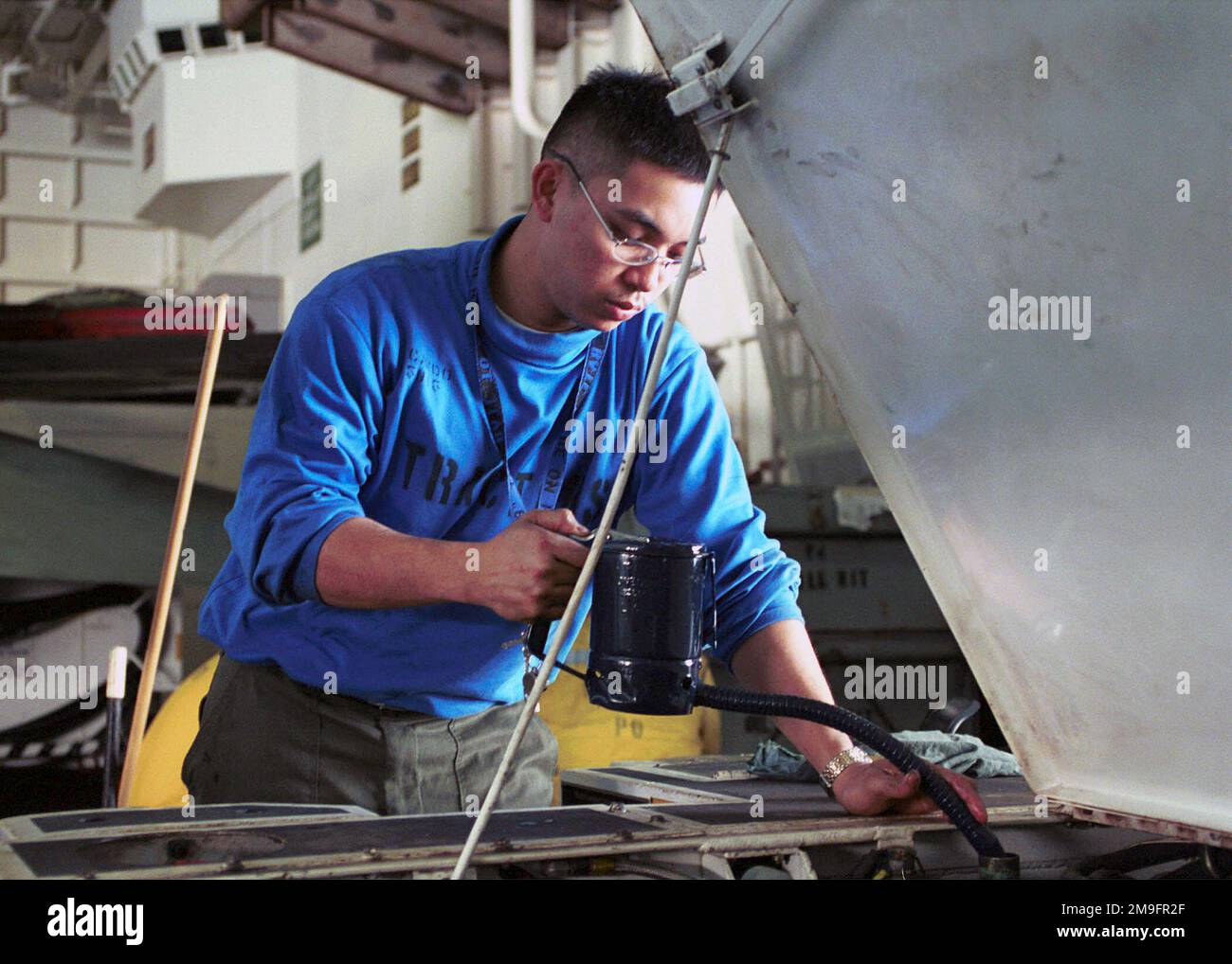Aviation Boatswain's Mate (Handler) AIRMAN Jason Cando replenishes oil during maintenance on a ...