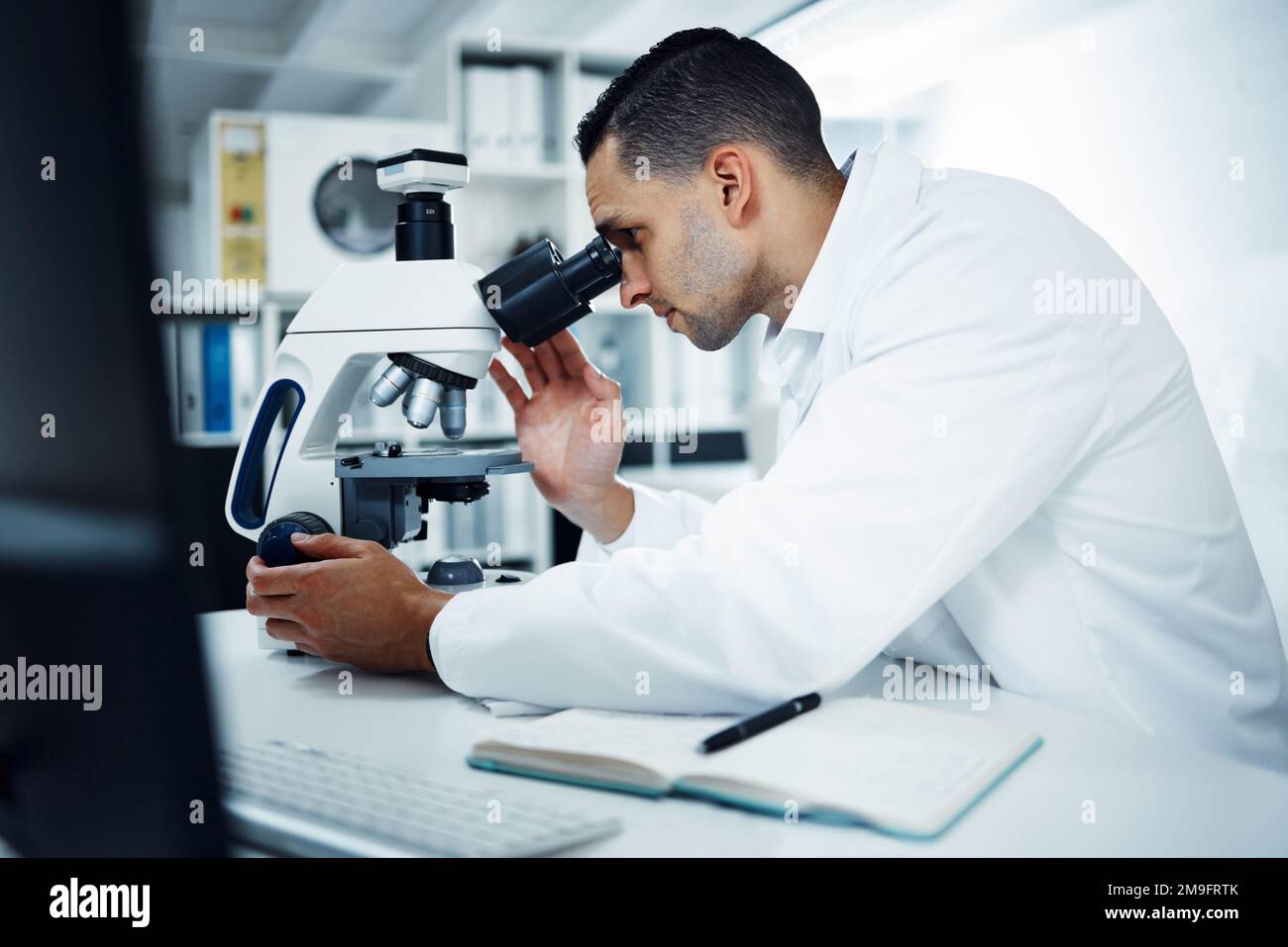 The answers lie under the lens. a young scientist using a microscope in ...