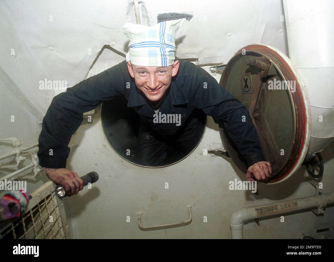 US Navy AIRMAN Richard Bailey exits through a scuttle after cleaning ...