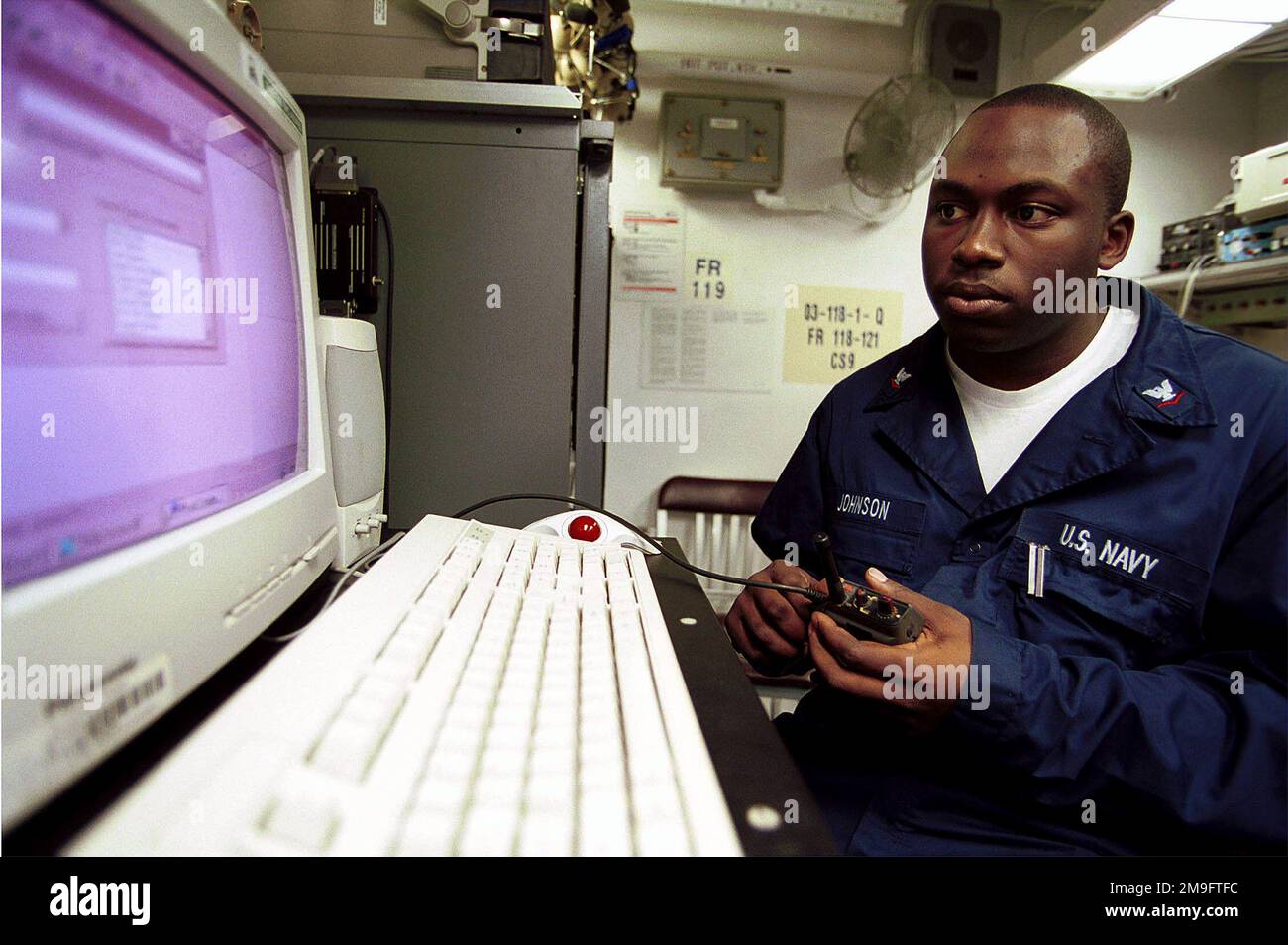US Navy Electronics Technician Third Class Michael Johnson programs a ...