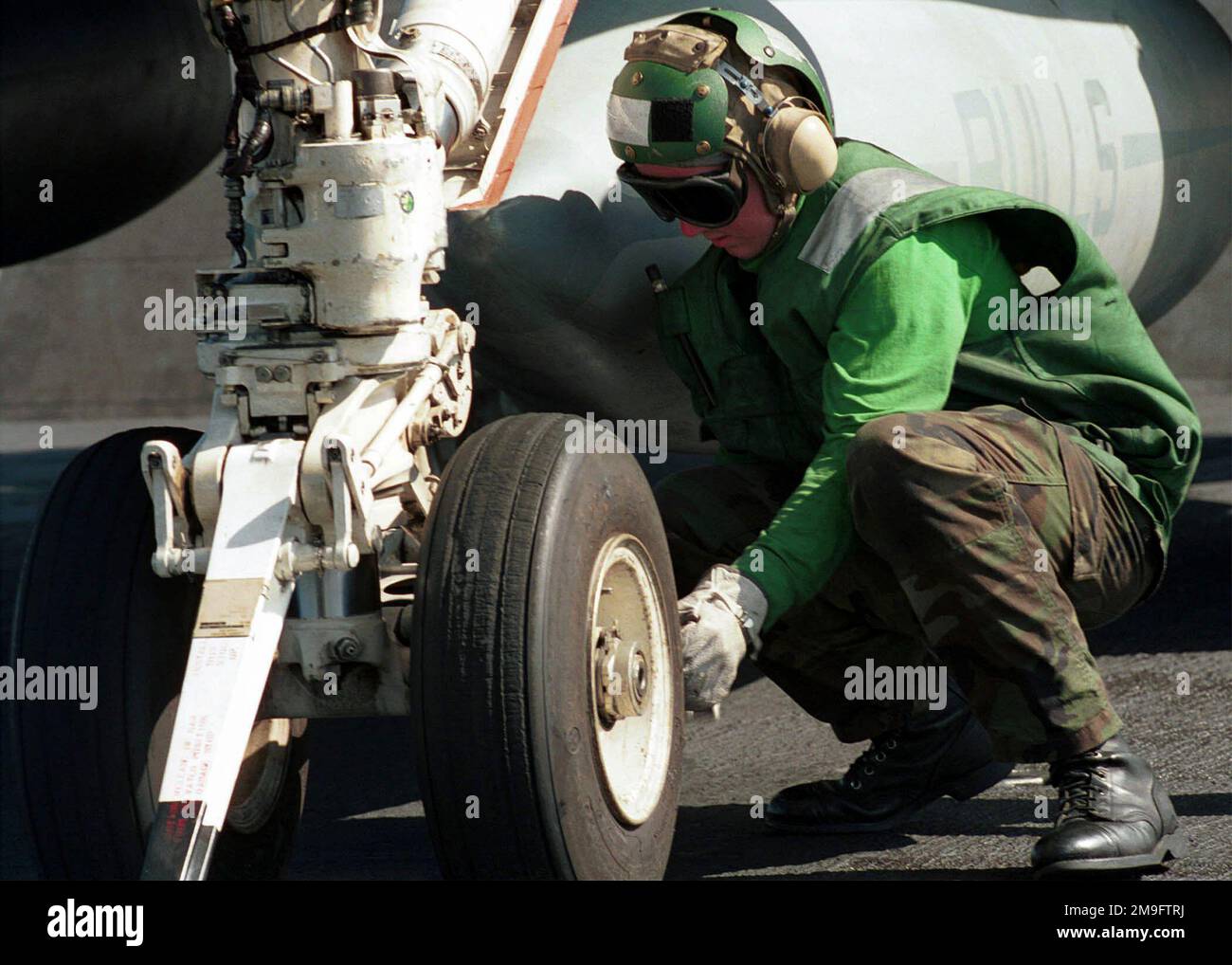 AIRMAN Tyron Miller, attaches a holdback bar to an F/A-18 Hornet from ...