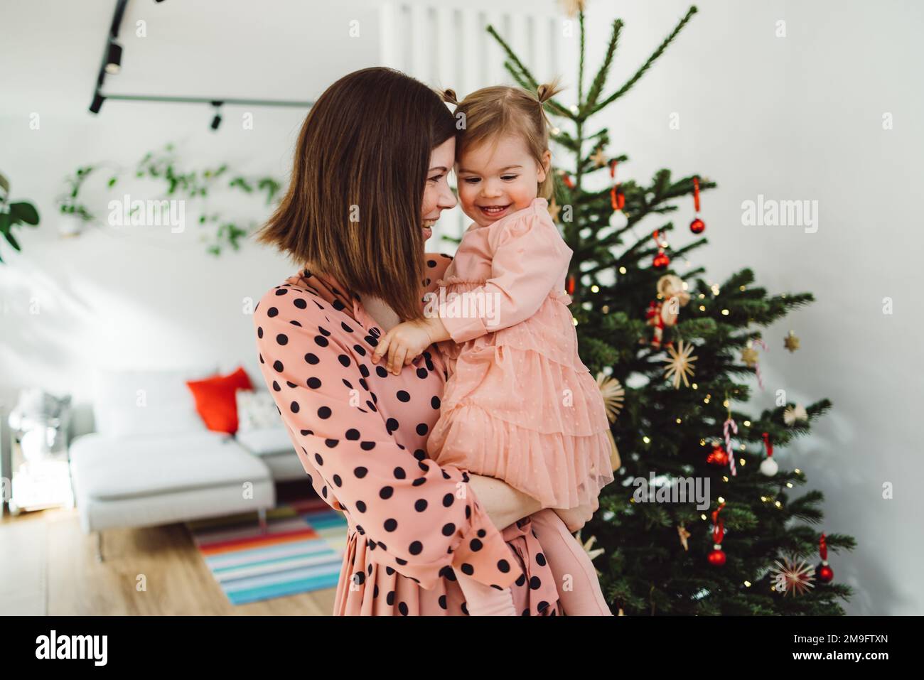 Young mom holding her little girl cuddling in her arms, standing in ...
