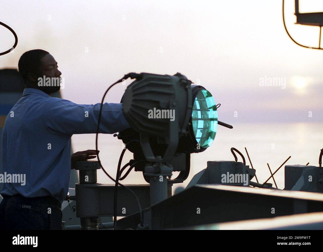 Signalman Second Class Kevin Lewis uses a signal light to signal ...