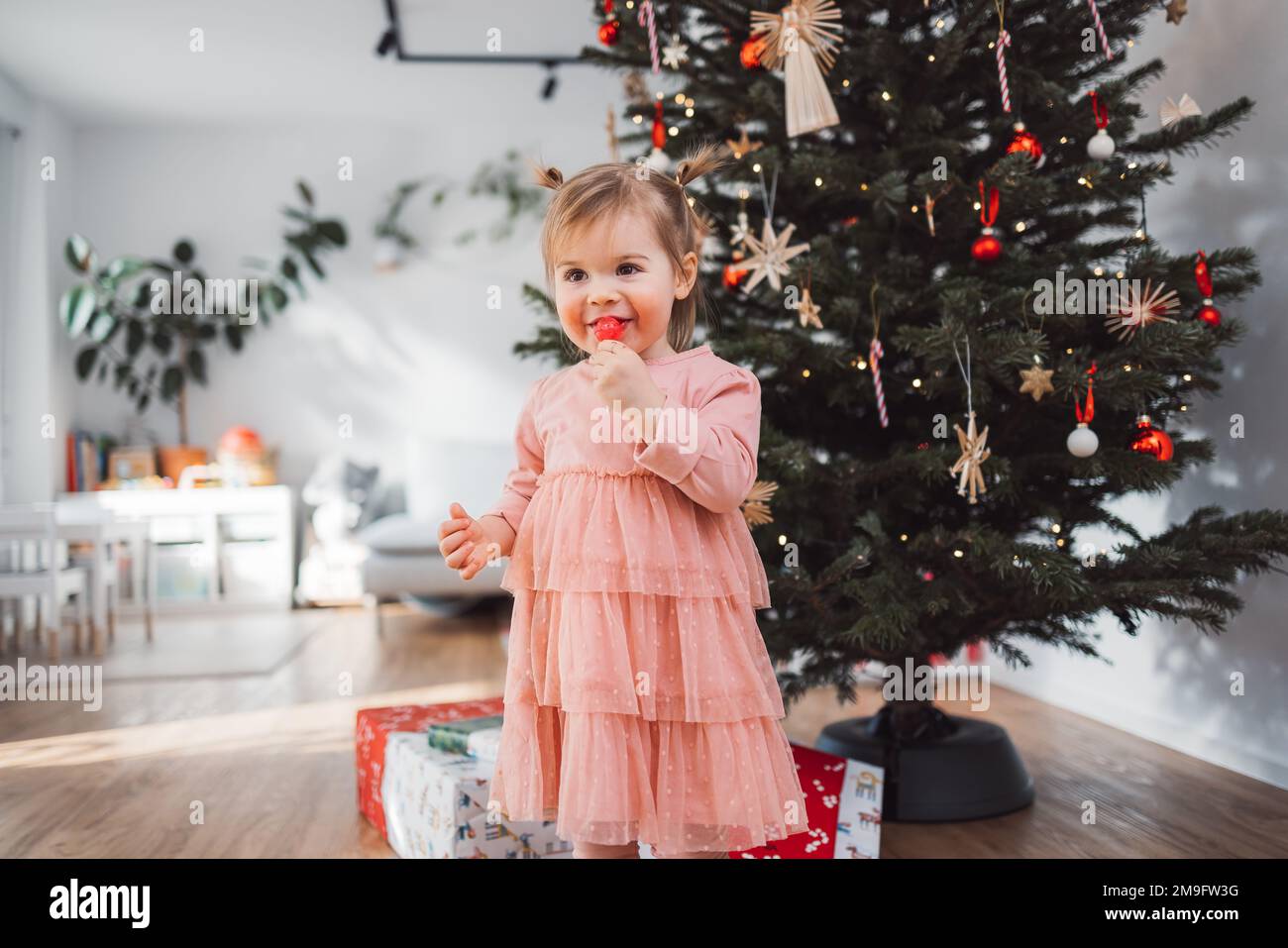 Cheerful little girl with a red lollipop, standing in front of the ...
