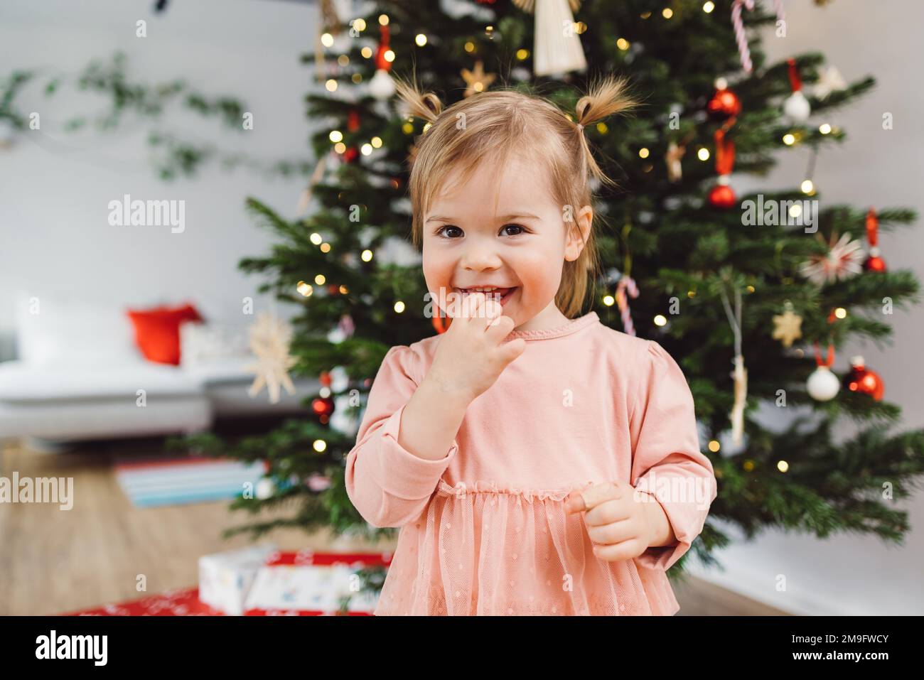 Cute little baby girl smiling at the camera chewing on her fingers ...