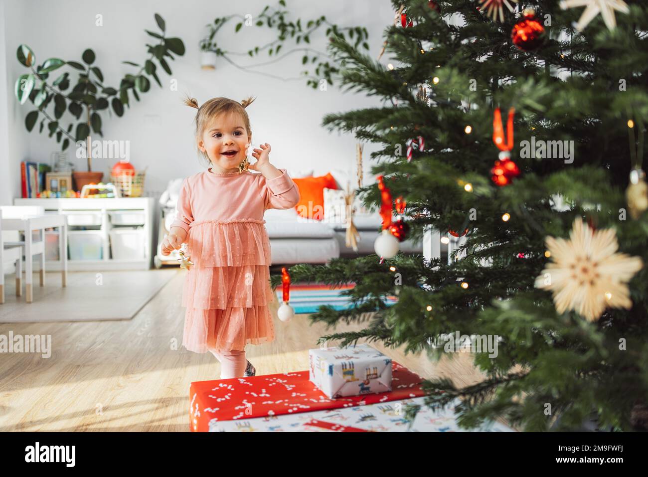 Joyfull little girl playing with Christmas ornament with a big smile on ...