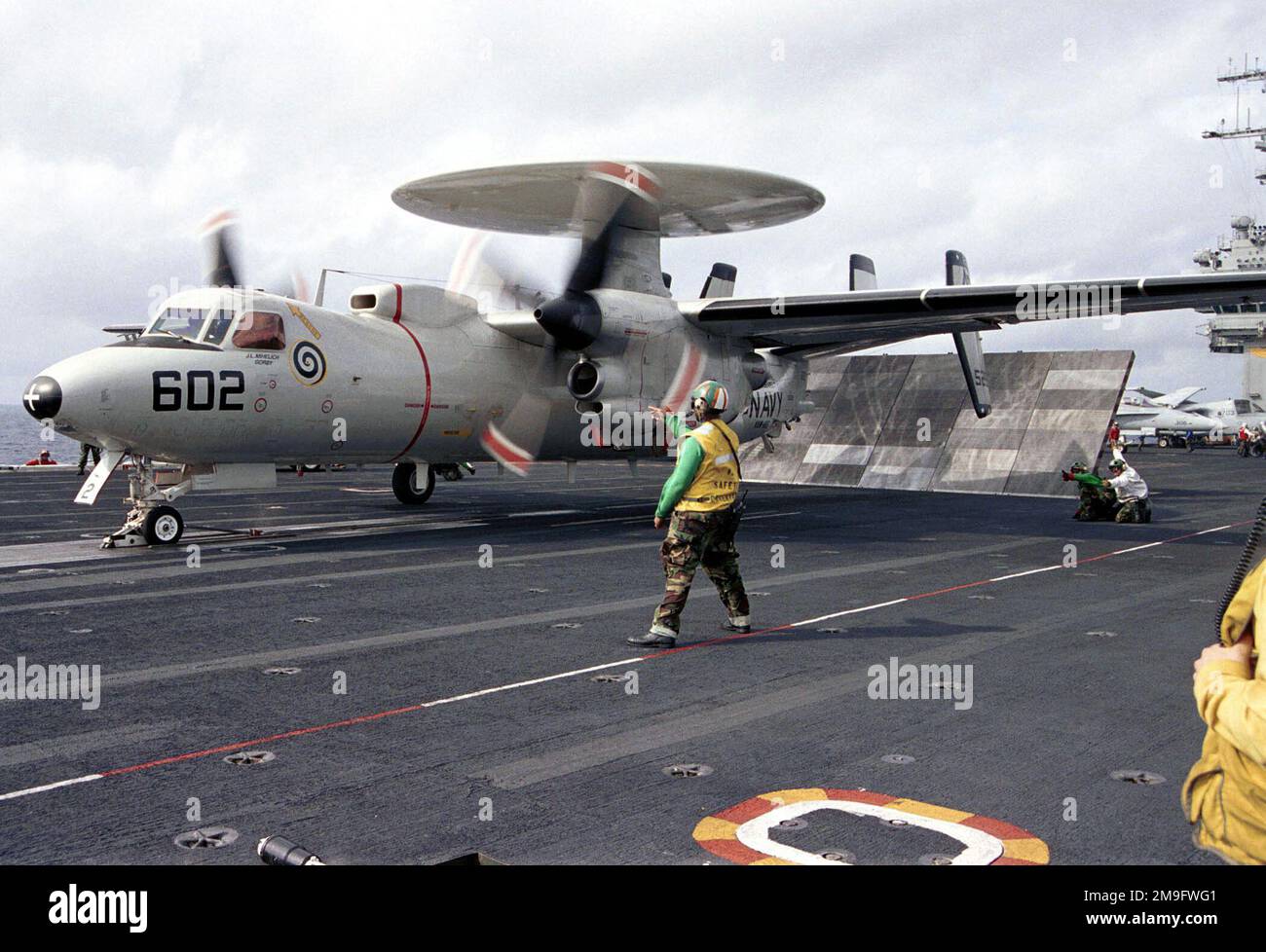 Aircraft handlers standby as the E-2 Hawkeye, from VAW-123, "screwtops ...