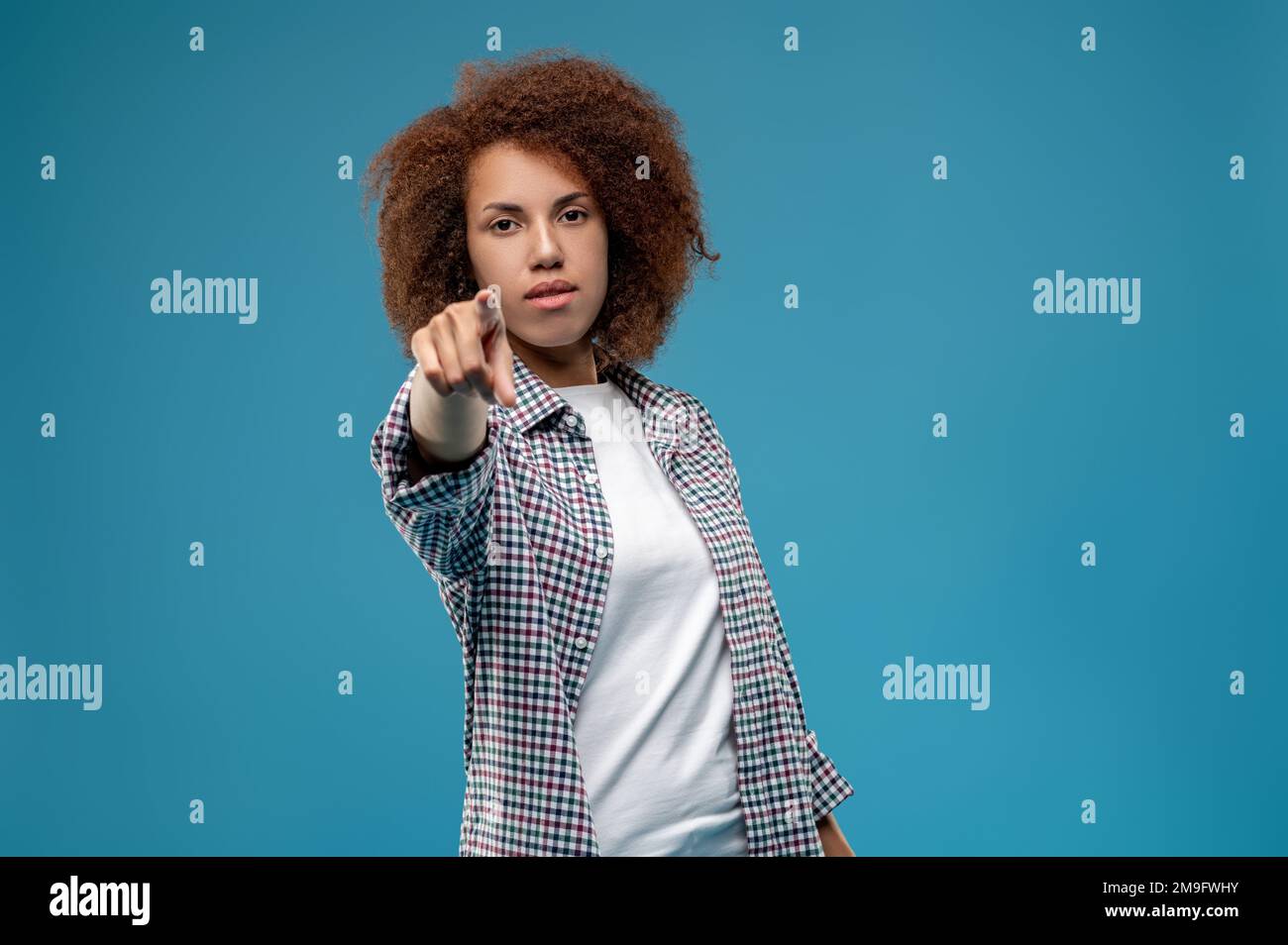 Young woman pointing to someone with her finger with a blaming look ...