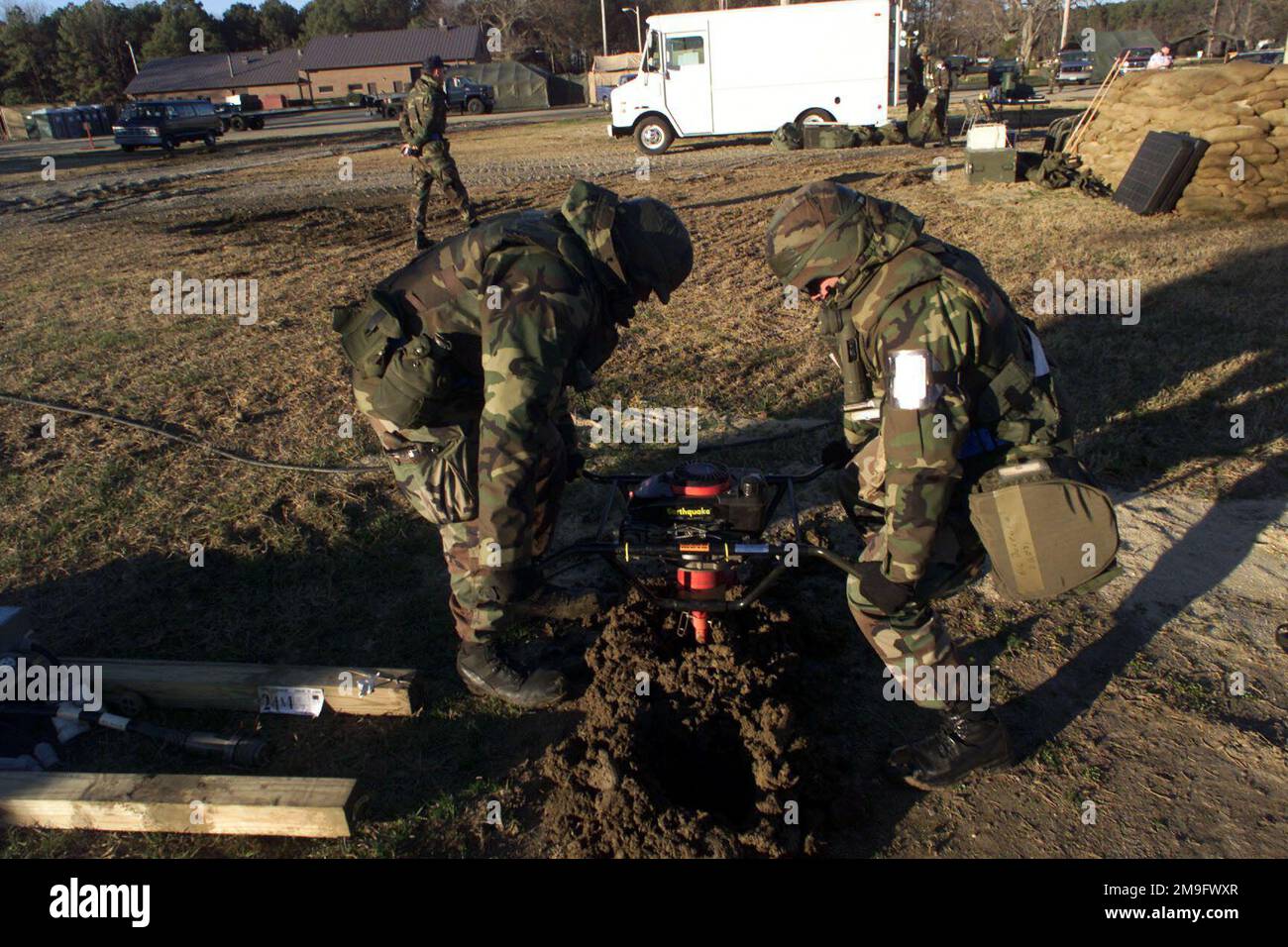 US Air Force Civil Engineers use a motorized auger to drill holes in ...