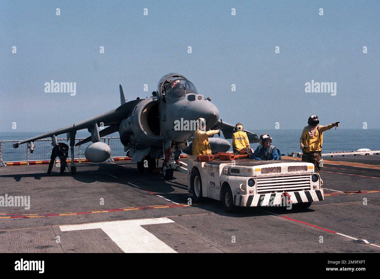 USS TARAWA (LHA 1) Sailors taxi an AV-8B Harrier aircraft into position ...
