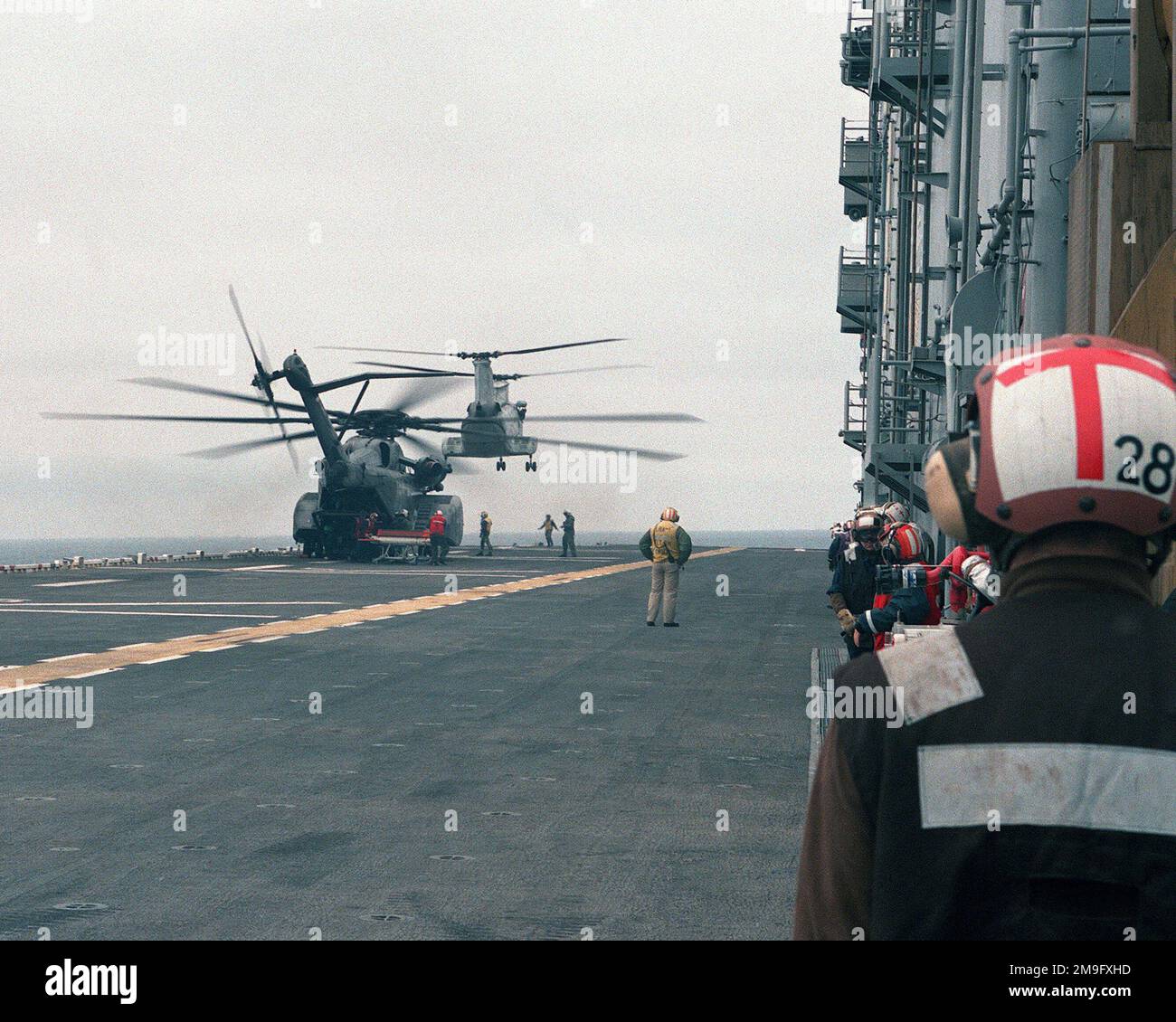 A CH-46 helicopter takes off and a CH-53 helicopter prepares to take ...