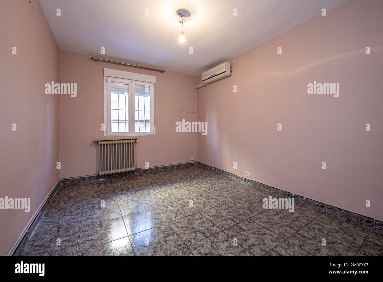 Long empty room with ugly dark tiled floor and pale pink painted walls ...