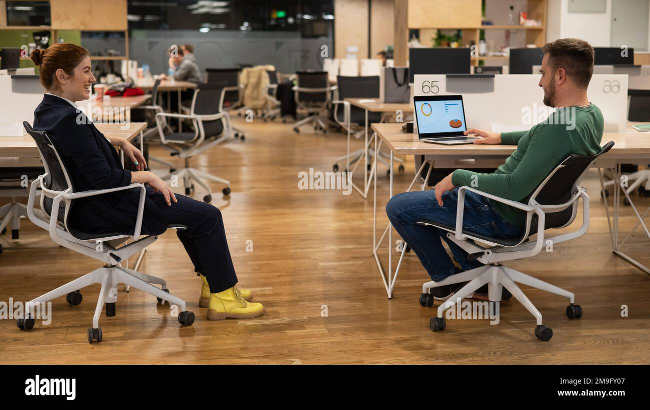 Redhead caucasian woman and bearded man are sitting on chairs in open ...
