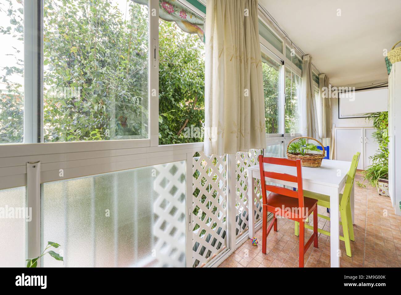 Closed terrace of a house with a white table and indoor hanging plants ...