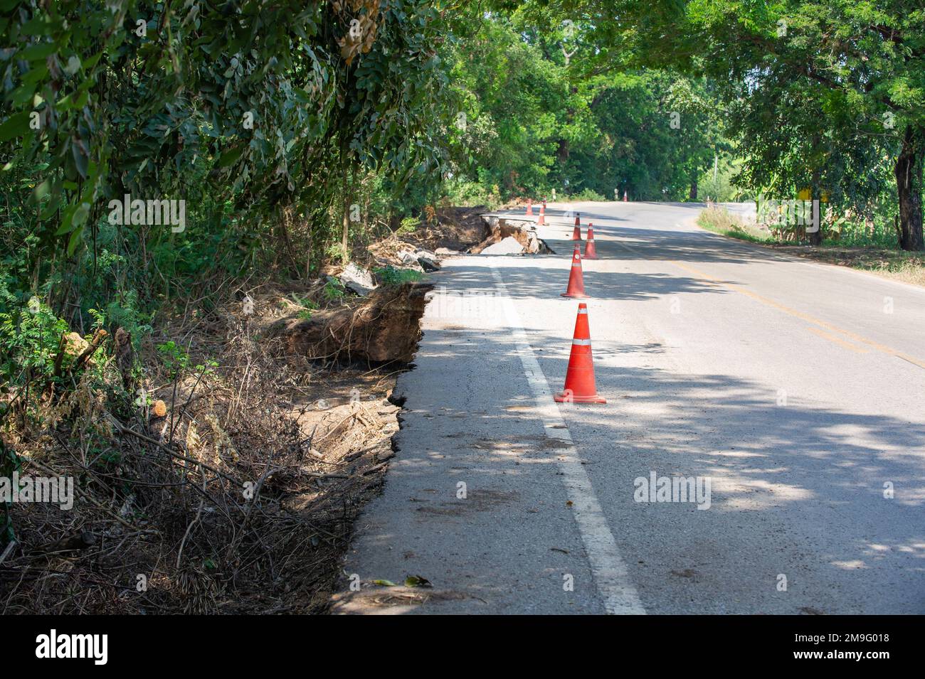 A Dangerously Eroded Road With Potholes And Warning Cones Stock Photo ...