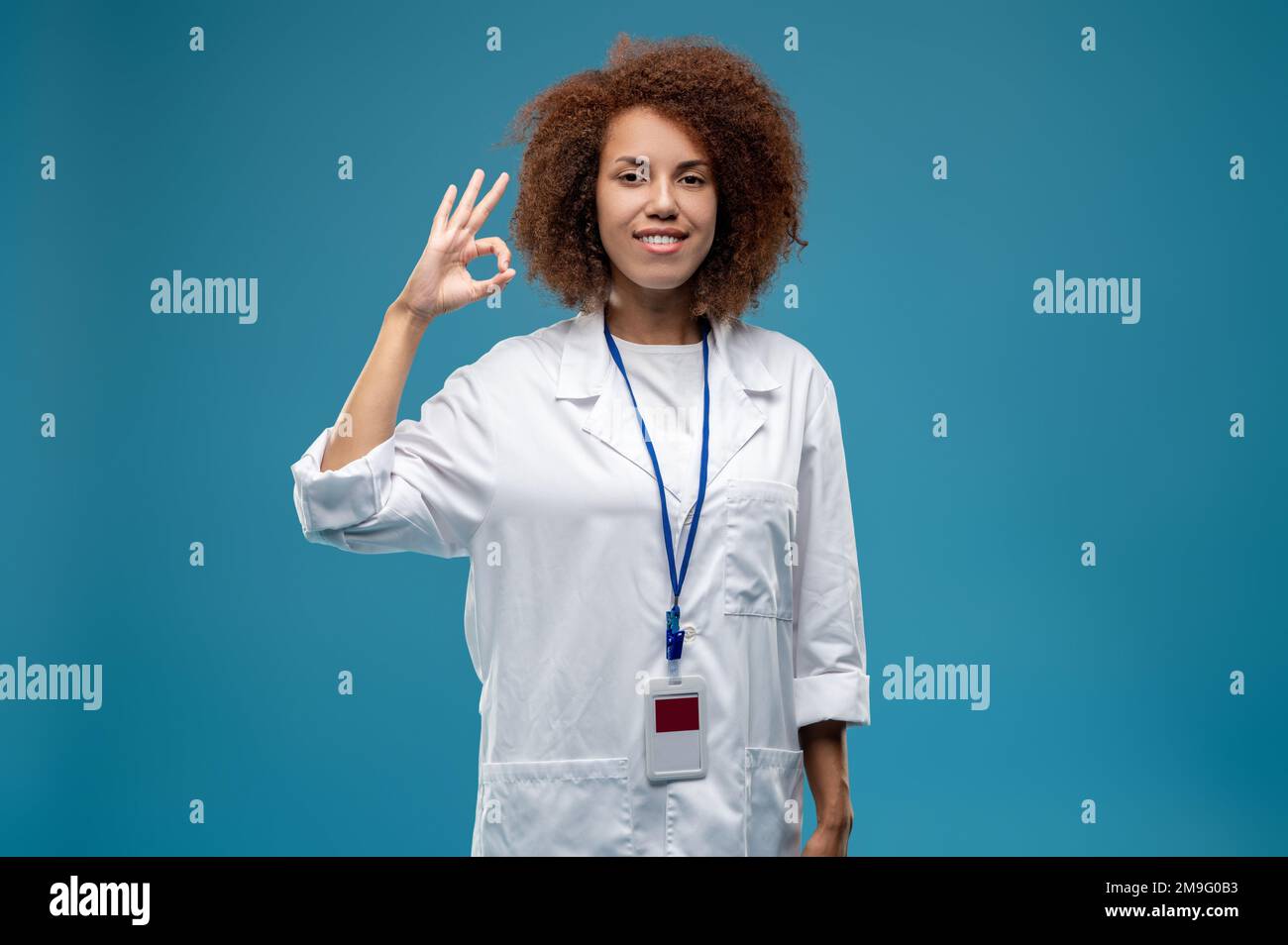 Pretty woman in a lab coat showing OK sign Stock Photo - Alamy