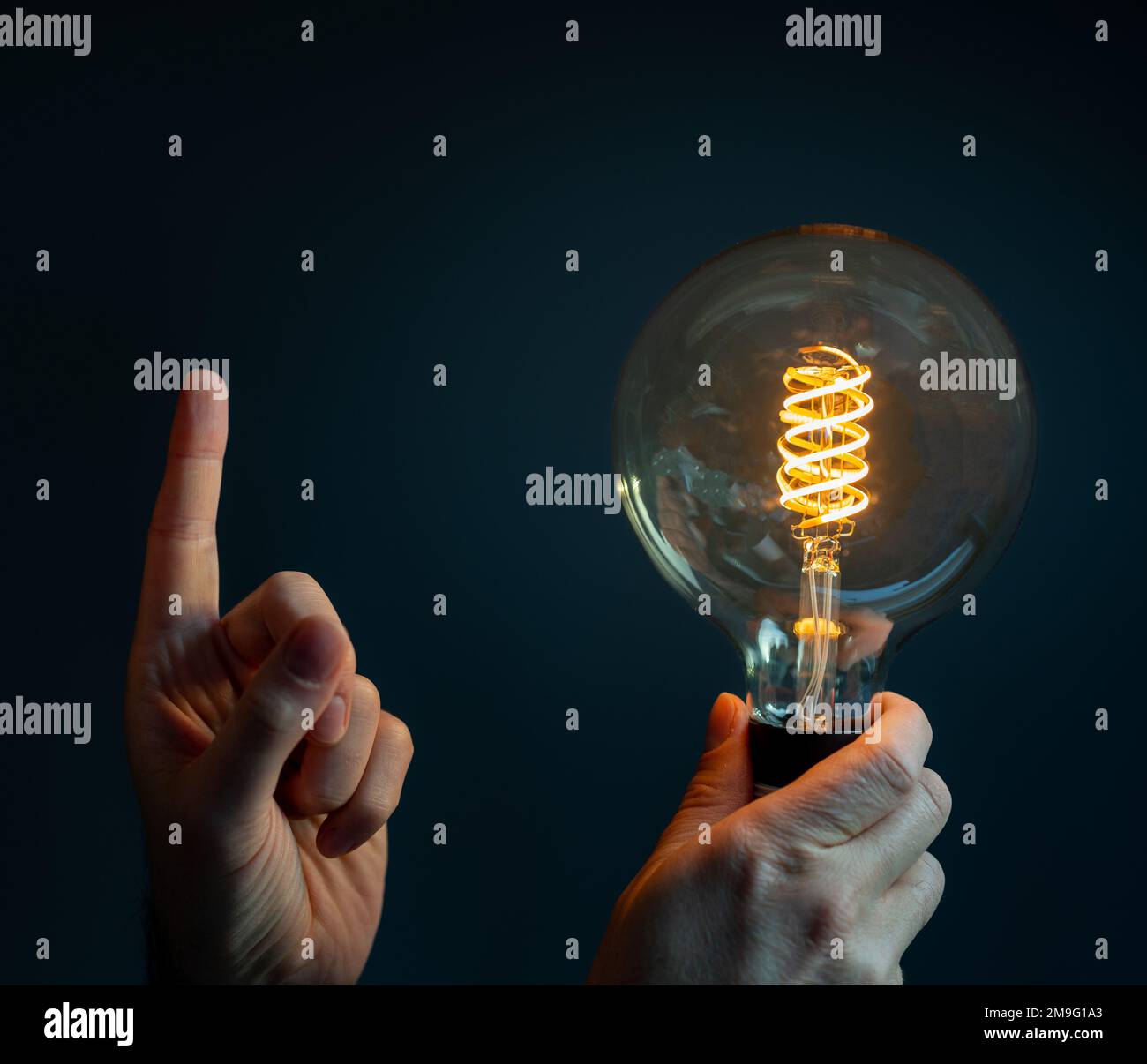 Symbol for saving energy. Hand holds a filament light-bulb where the ...