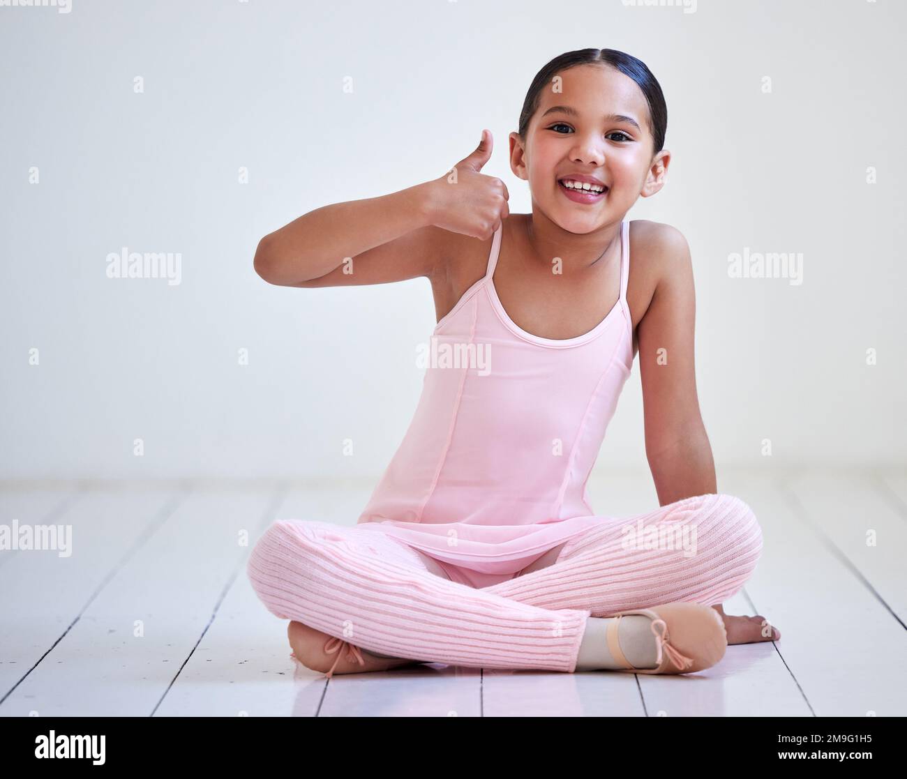 I love learning ballet. Portrait of a little girl showing thumbs up in ...