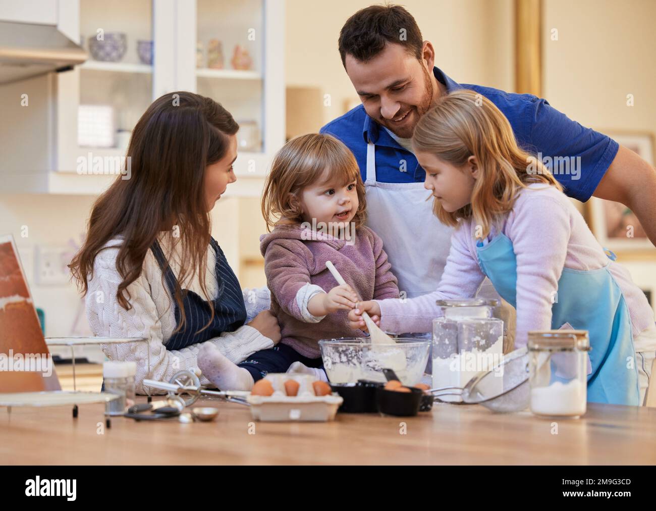 You both can take turns. a family baking together while a little girl ...