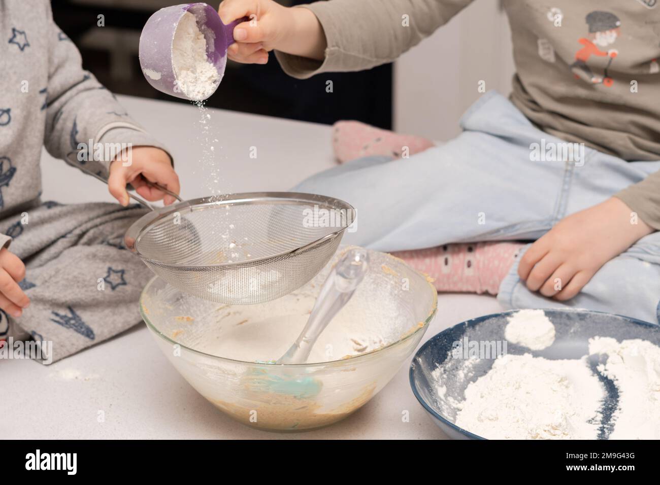 children adding flour to a large sieve for a cake mixture Stock Photo ...