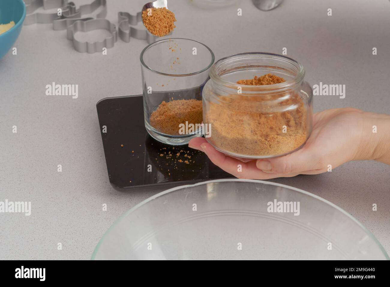 woman weighing brown sugar on a scale in her kitchen to bake a cake ...