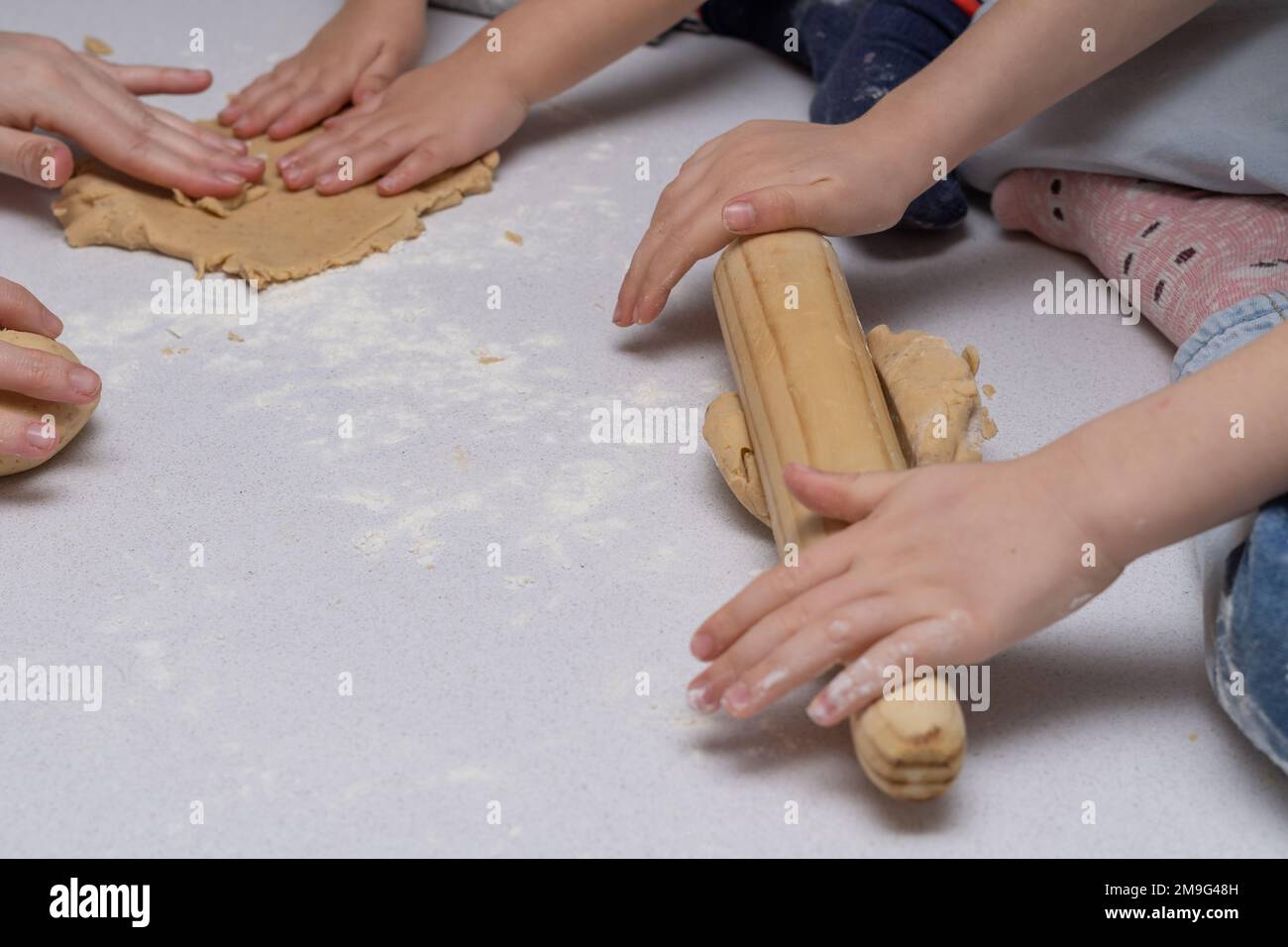 boy kneading cookie dough with a wooden rolling pin and his brother's ...