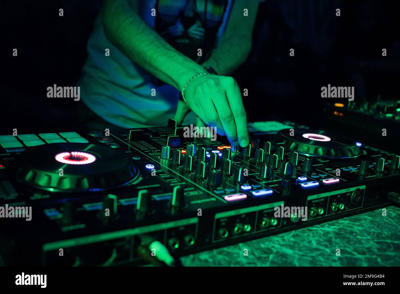 hands DJ mixing and playing music on a professional controller mixer ...