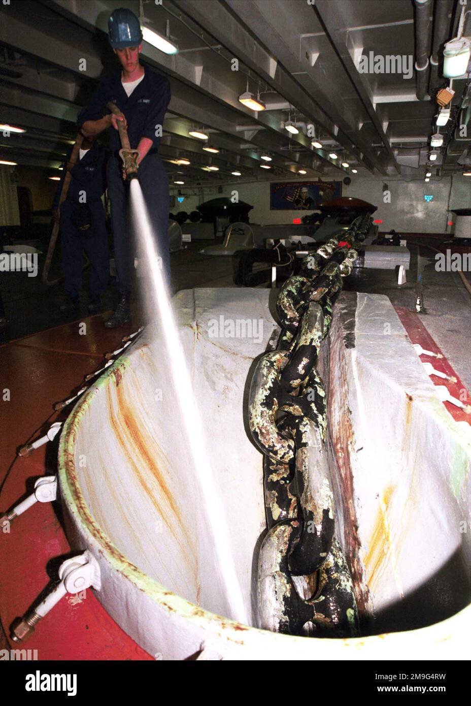 US Navy SEAMAN Kevin Rohrer washes down the anchor chain as it is ...
