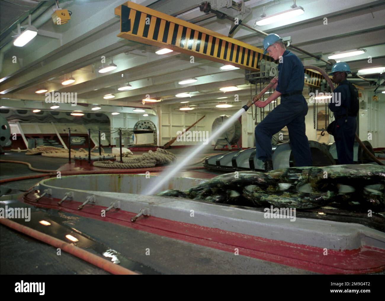 US Navy SEAMAN Kevin Rohrer washes down the anchor chain as it is ...