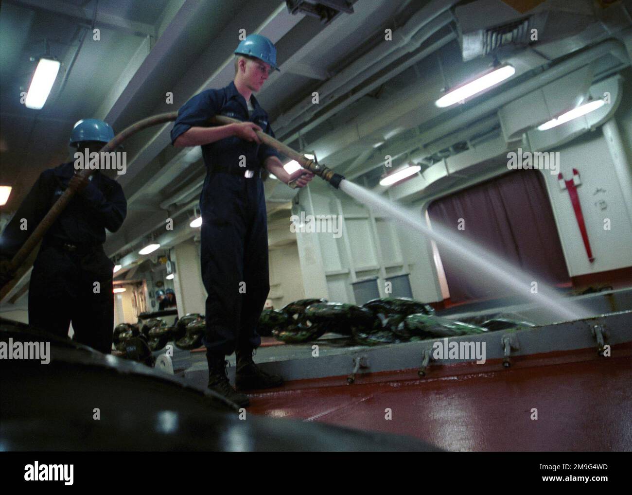 US Navy SEAMAN Kevin Rohrer washes down the anchor chain as it is ...