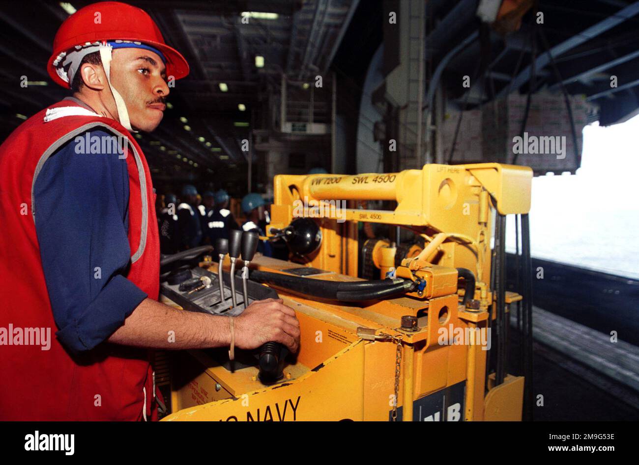US Navy AIRMAN William Bowdin III drives a forklift while moving ...