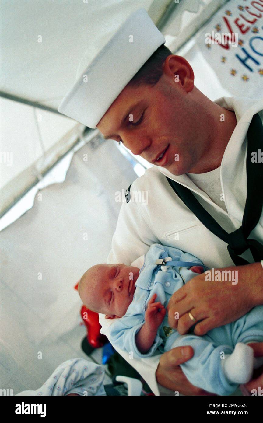 A Sailor holds his baby on Pier 12 at Naval Station Norfolk as family ...