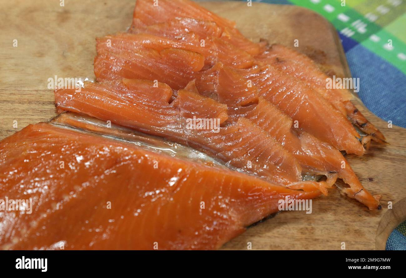 Partly sliced smoked salmon fillet skin-on photographed in the process ...