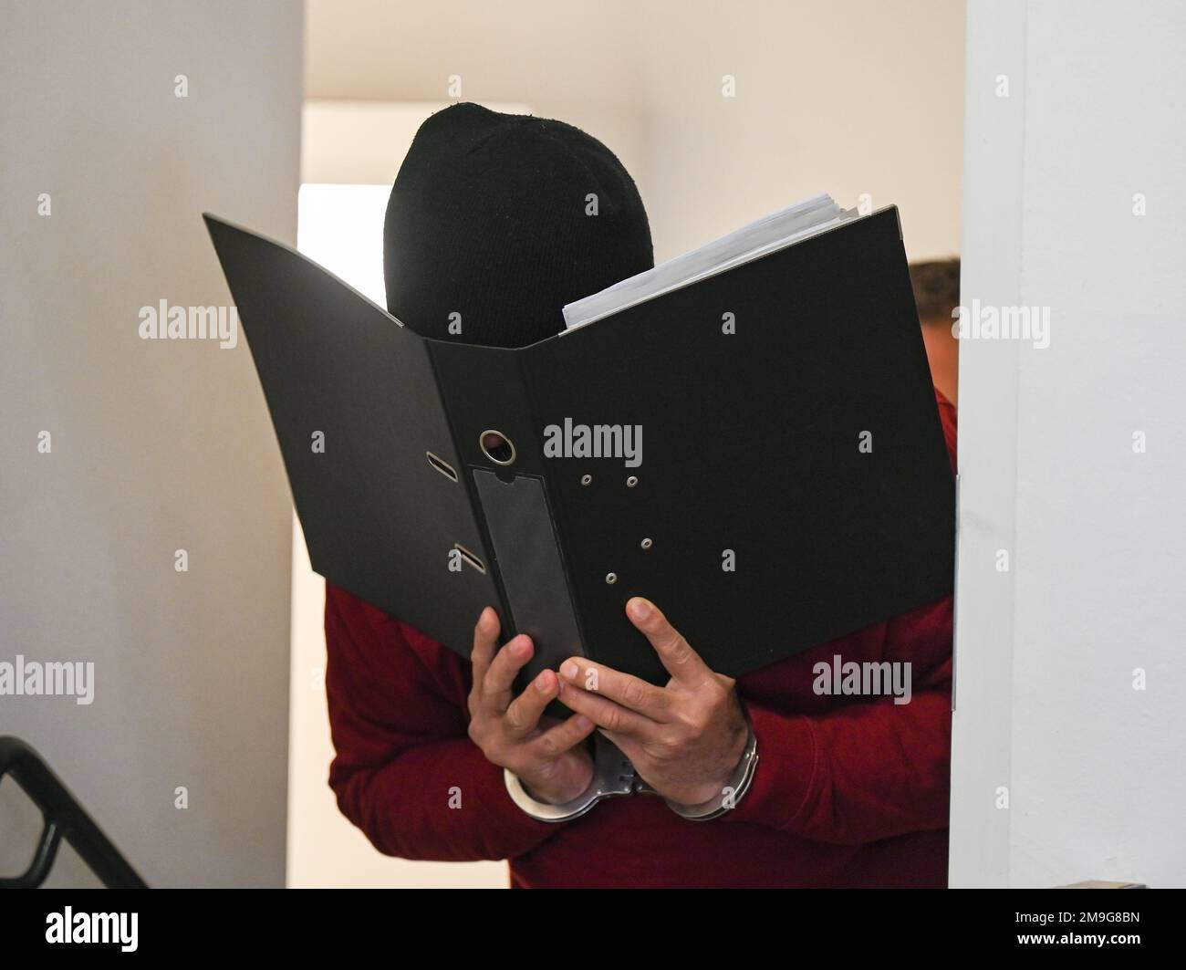 Hanau, Germany. 18th Jan, 2023. The defendant, handcuffed and hiding ...