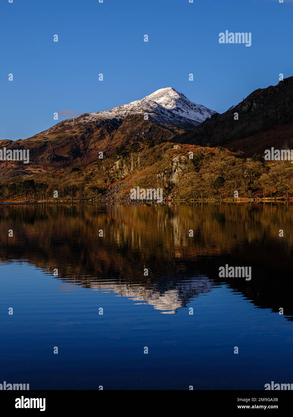 Perfect reflection of snow covered mountains in a lake in Snowdonia National Park, North Wales ...